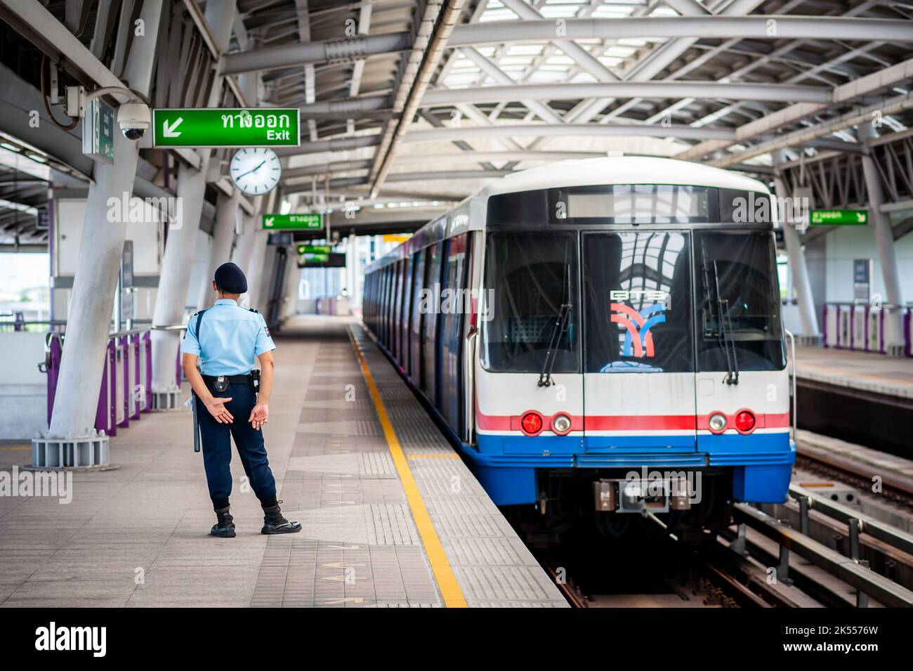 A smart Thai train guard watches the public and trains on the platform ...