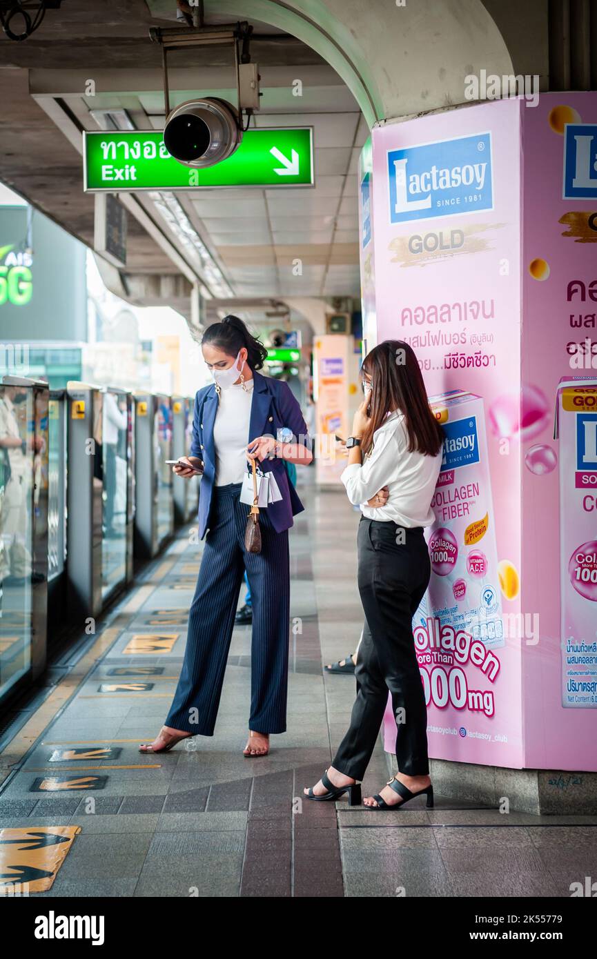 Smart and stylish Thai business women wait at Siam BTS sky train ...