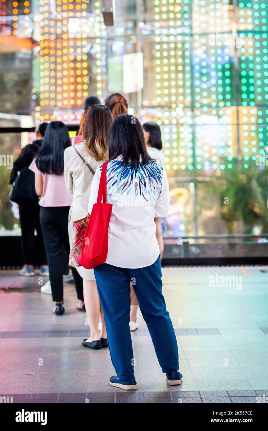 A queue of Thai commuters wait for their BTS sky train at Siam train station, Bangkok, Thailand ...