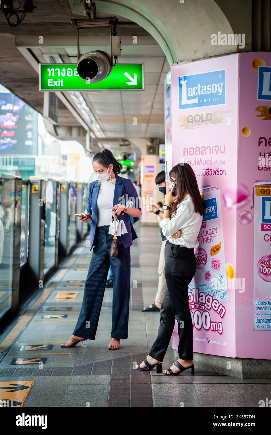 Smart and stylish Thai business women wait at Siam BTS sky train ...