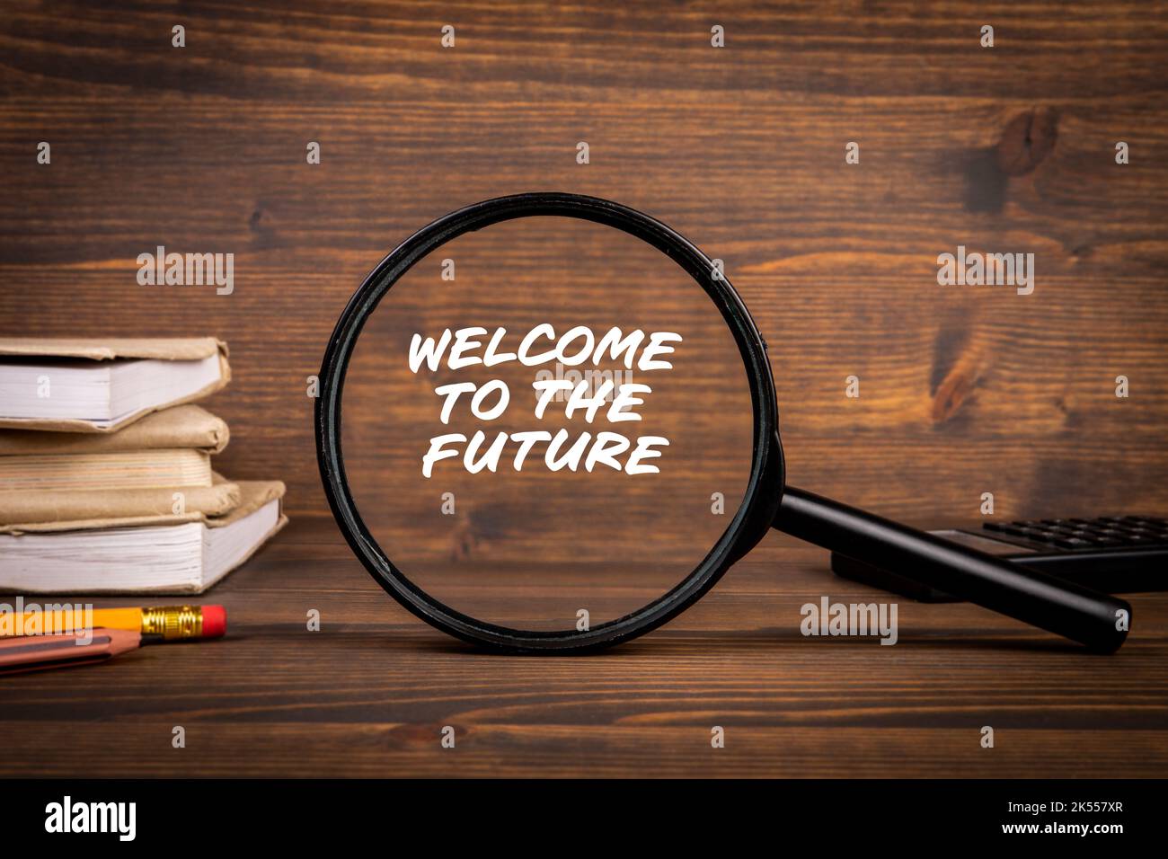 Welcome to the Future. Magnifying glass and stack of books on wooden ...