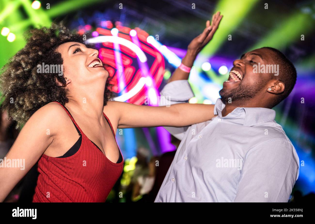Multiracial young couple dancing at night club with laser light show ...