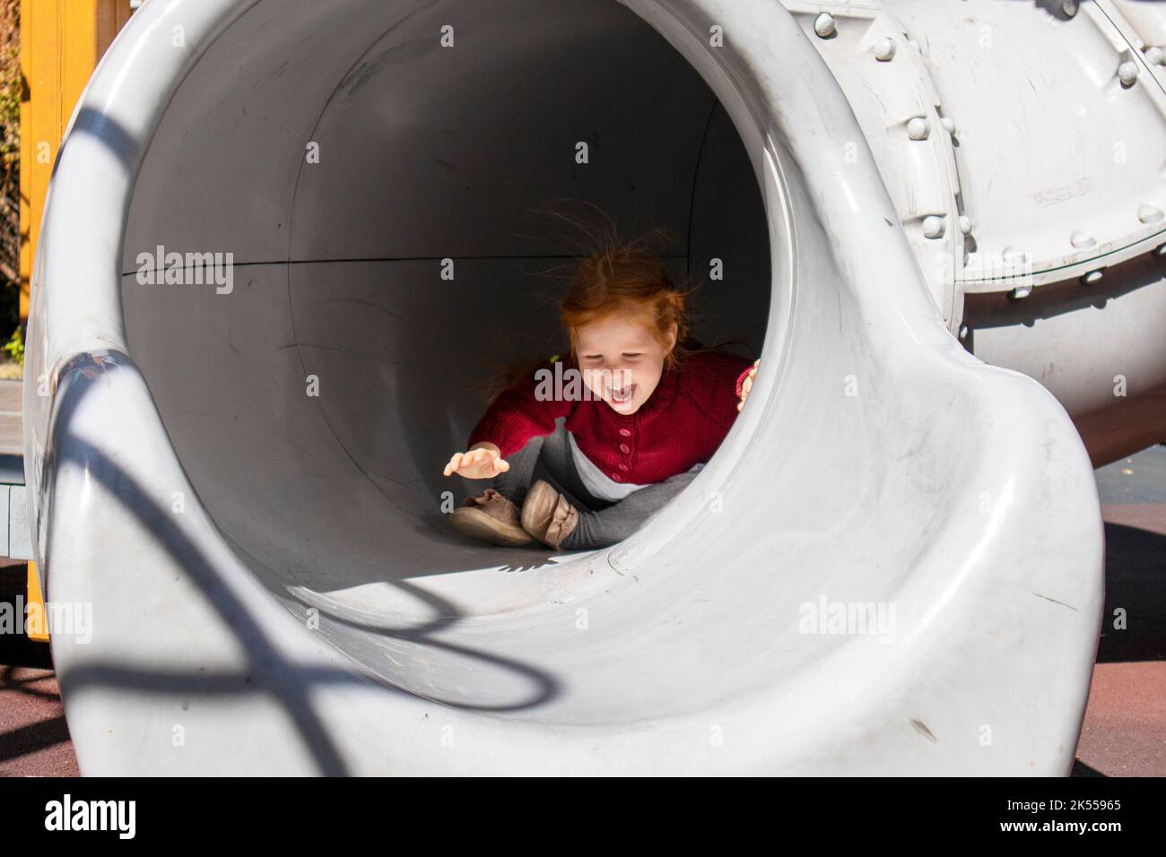 a red-haired little girl rolled down a pipe slide Stock Photo - Alamy