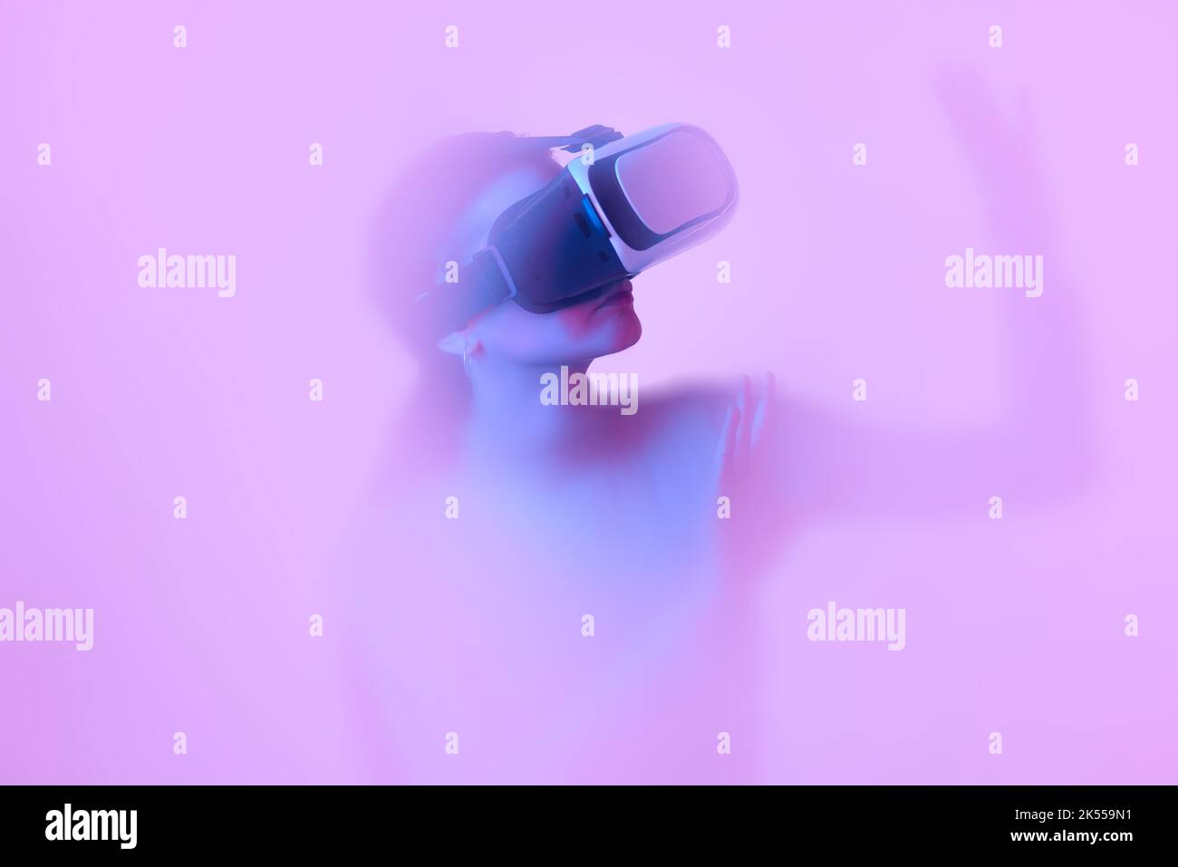 Female model in VR goggles immersed in clouds of smoke, fog on a pink ...