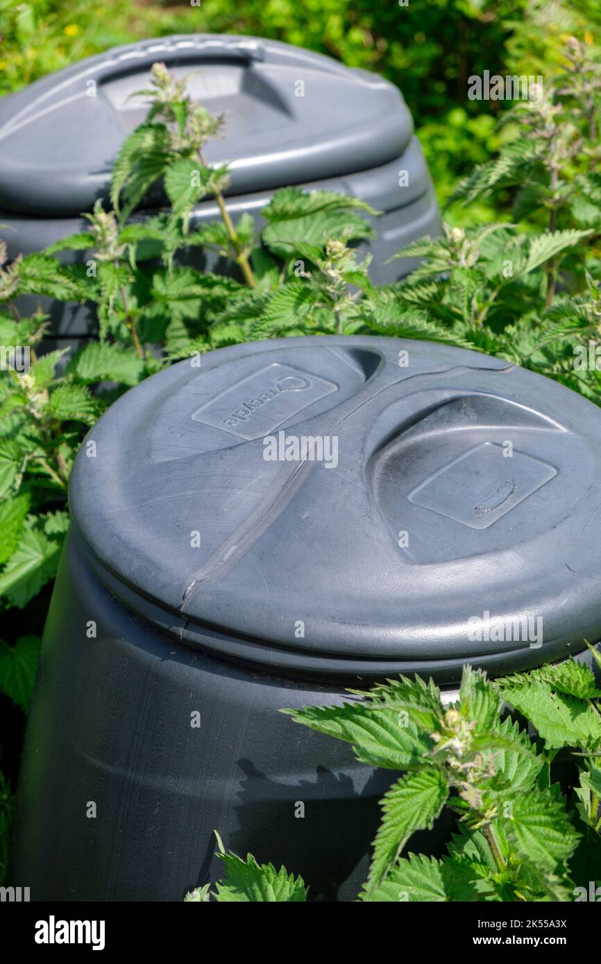 Two old plastic compost bins in an over grown garden Stock Photo - Alamy