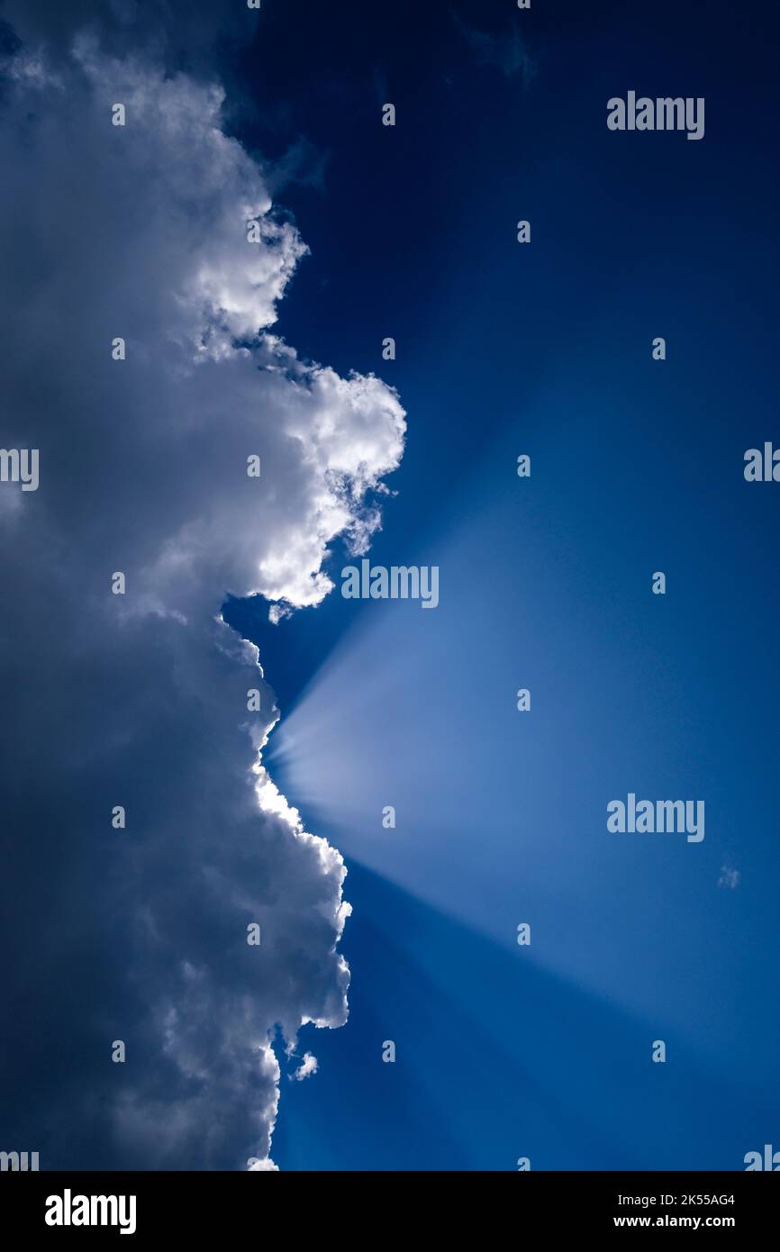 Huge clouds backlit by the sun with sun beams and rays escaping around ...