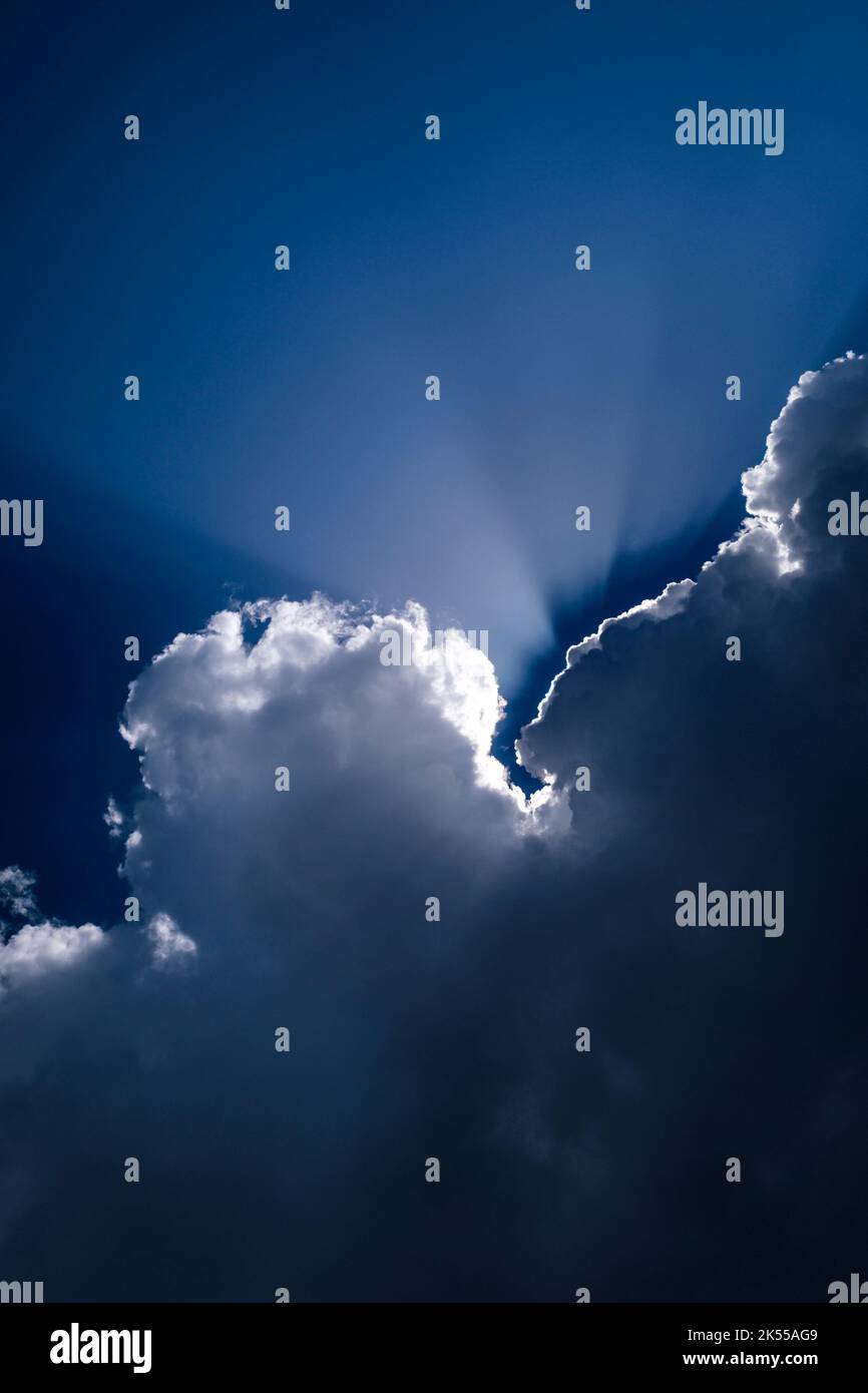 Huge clouds backlit by the sun with sun beams and rays escaping around ...