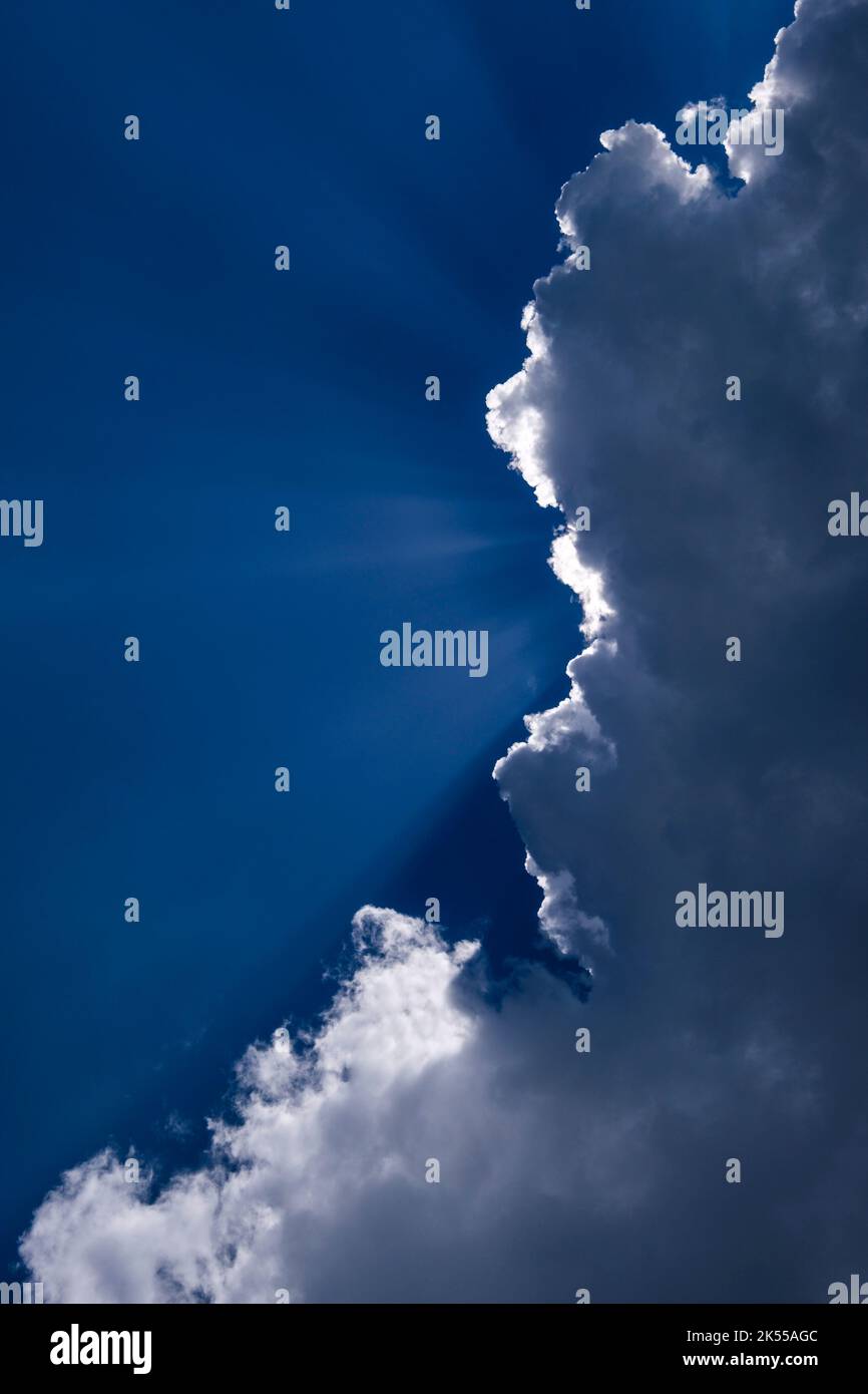 Huge clouds backlit by the sun with sun beams and rays escaping around ...