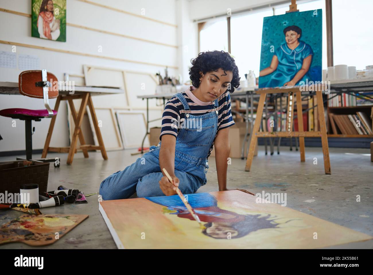 Painter, woman artist and creative on floor painting canvas in studio ...