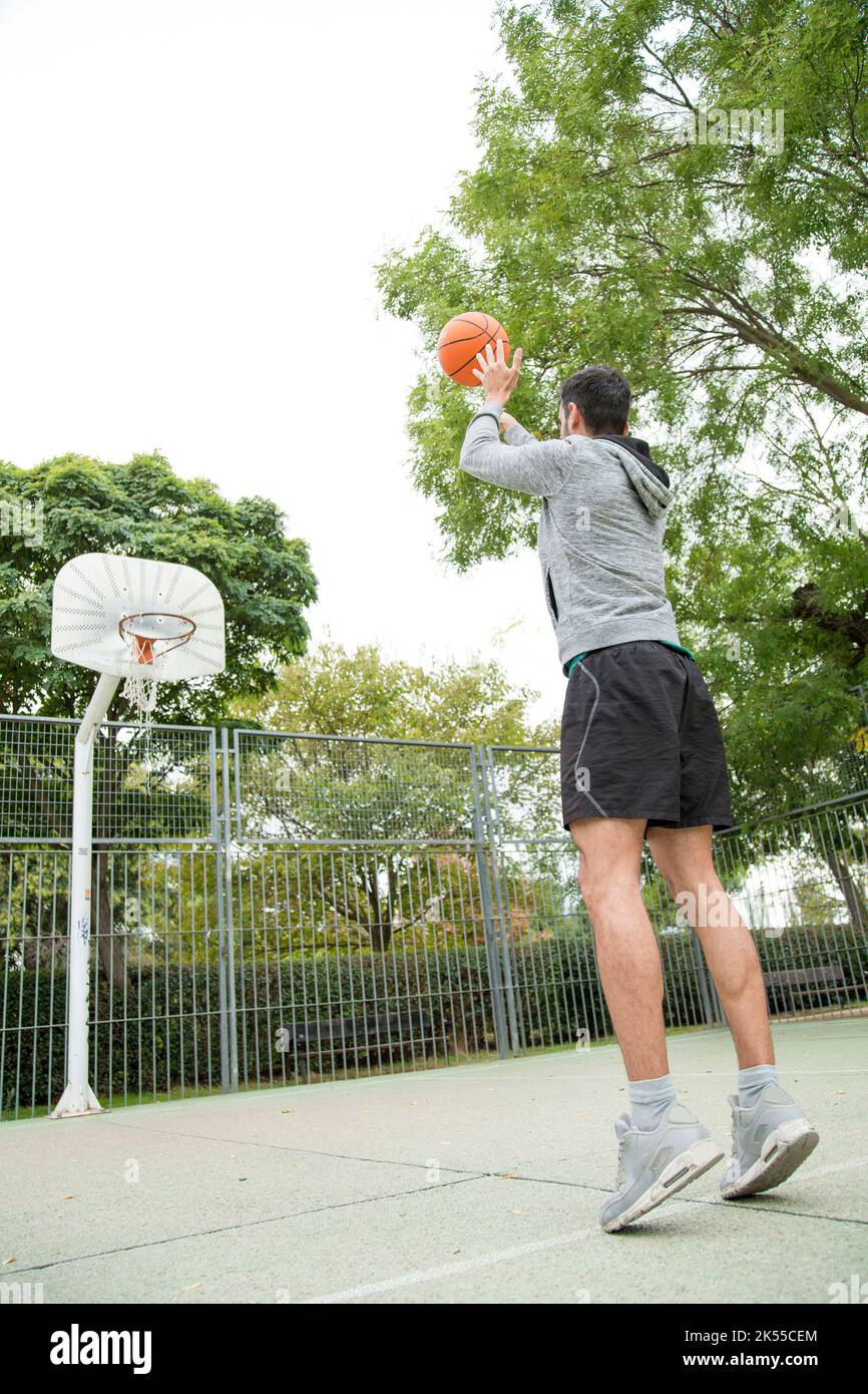 Vertical photo of the rear view of a basketball player training alone ...