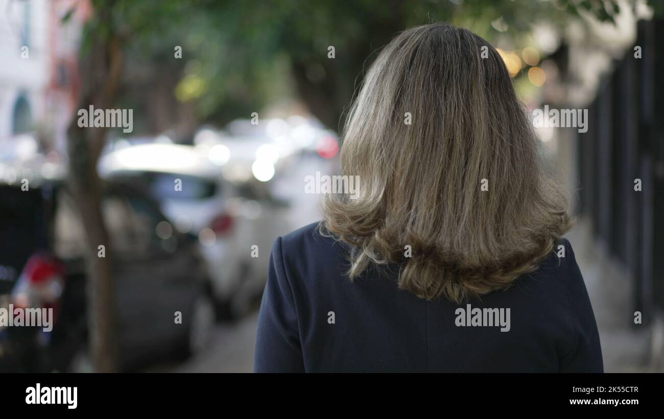 Back of person walking in city street. Contemplative woman walks ...