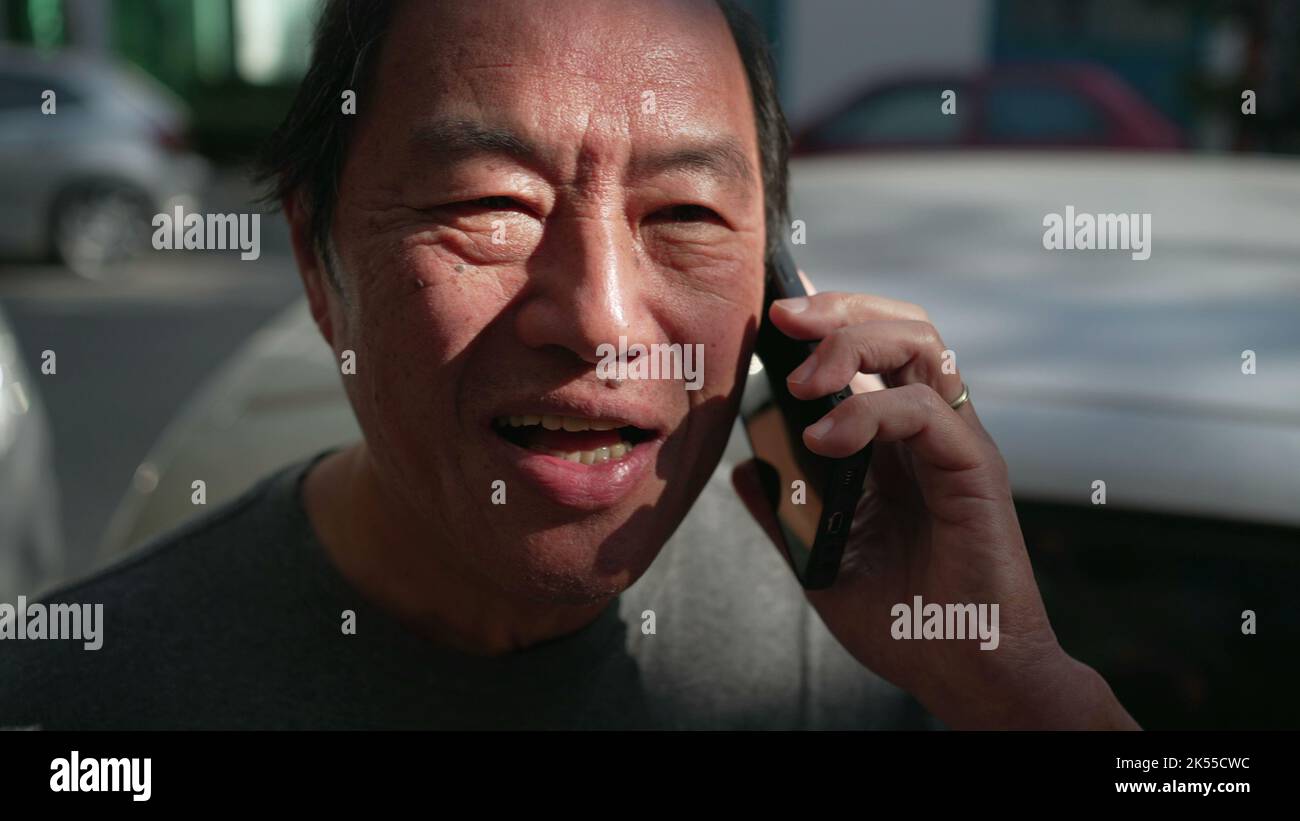 Asian American man speaking on phone in urban street. Portrait of a ...