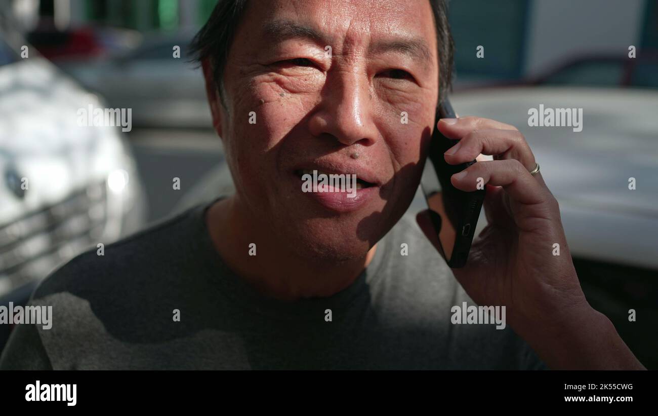 Asian American man speaking on phone in urban street. Portrait of a ...
