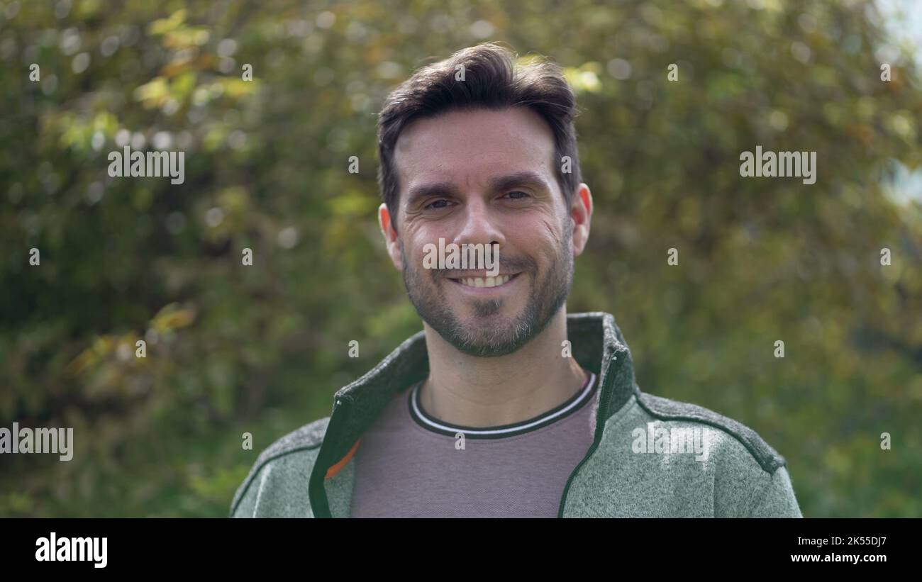 Happy handsome man smiling at camera. Portrait face closeup standing outdoors. 30s male person ...