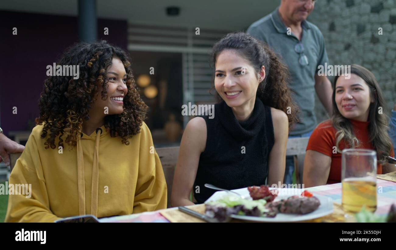 Friends conversing outdoors in home backyard barbecue. Diverse group of ...