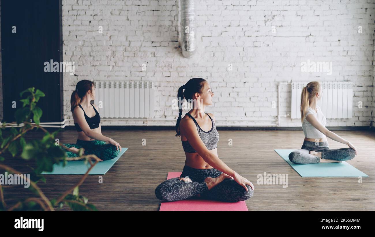 Pretty slim girls are doing yoga exercises under guidance of ...
