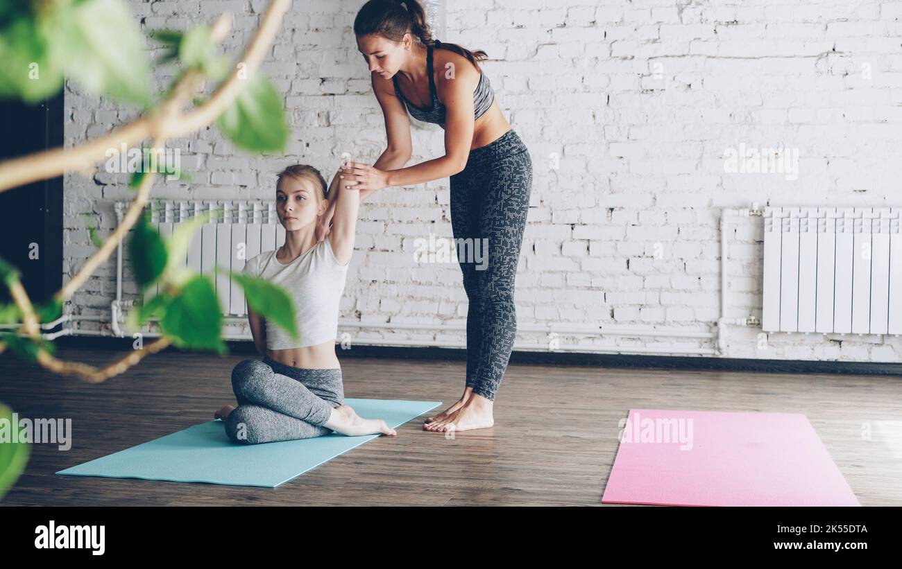 Pretty blond female yoga student is learning arm twists in cow face ...