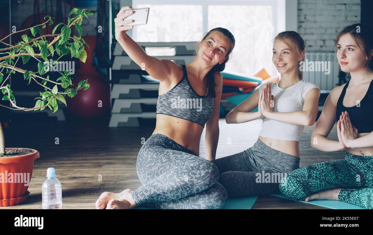 Yoga students are taking selfie with smartphone while sitting together ...