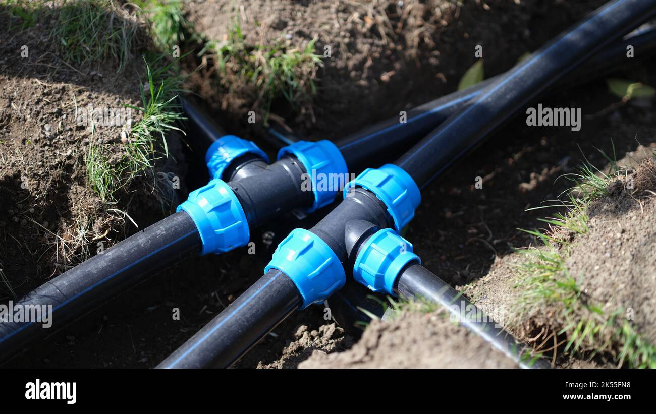 Black long pipe lies and tee adapter in dug-out earth closeup Stock ...
