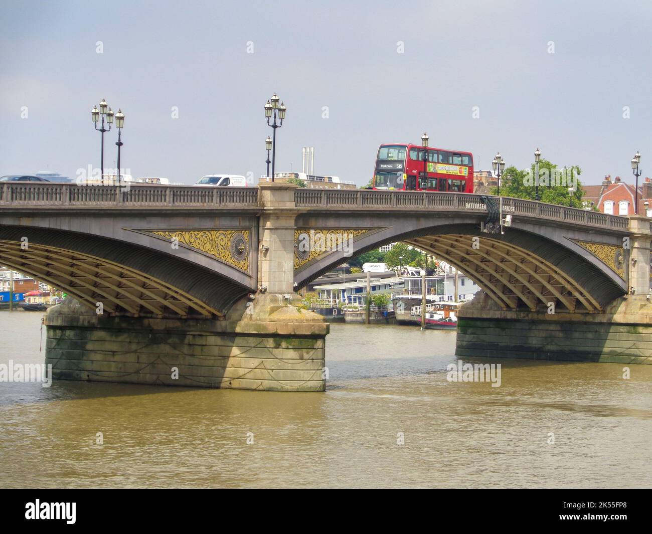 Red London bus (public transport) crossing Battersea Bridge that links ...