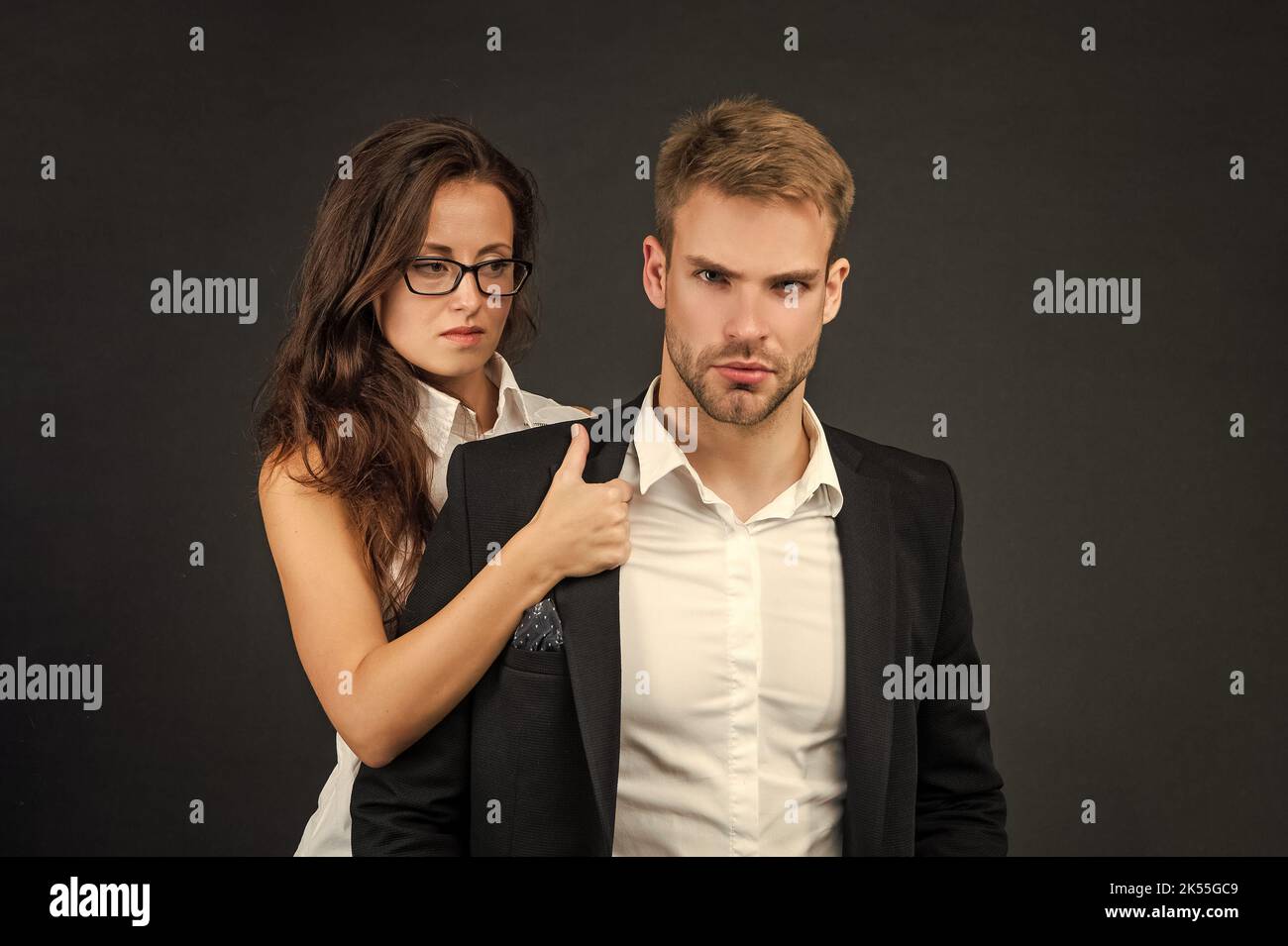 elegant man and woman in business look on black background, relations ...