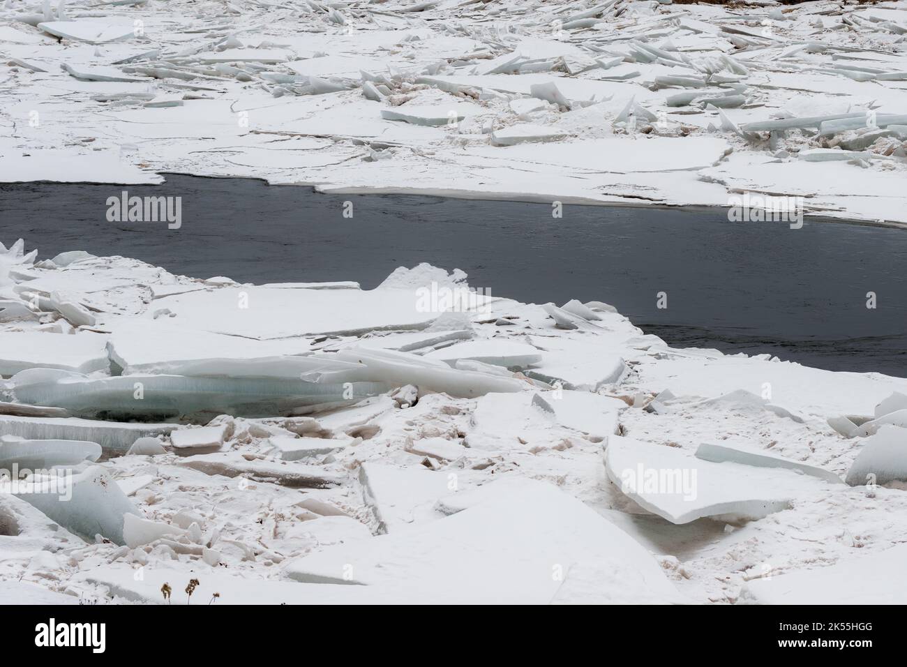 Ice jammed river. Large slabs of broken jagged ice clog the river. The ...