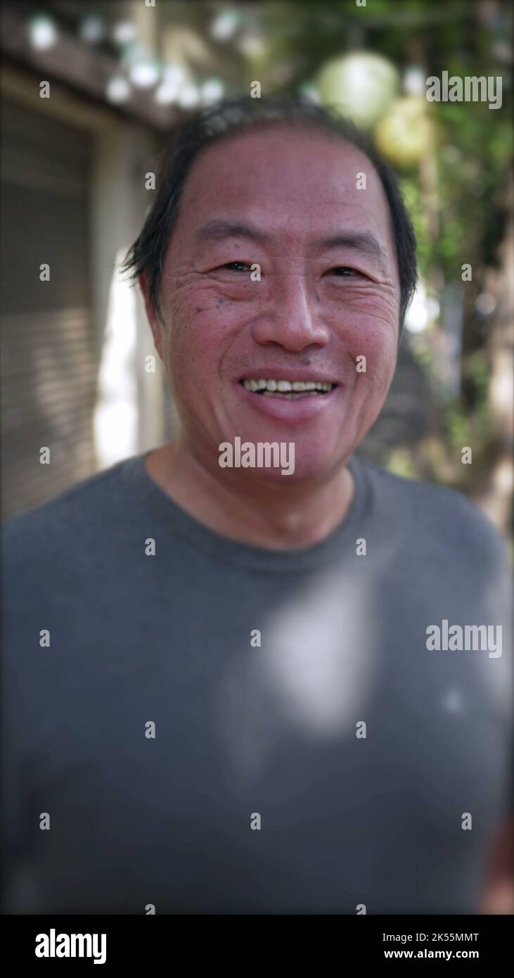 Portrait of a middle aged Asian American man smiling standing in street ...
