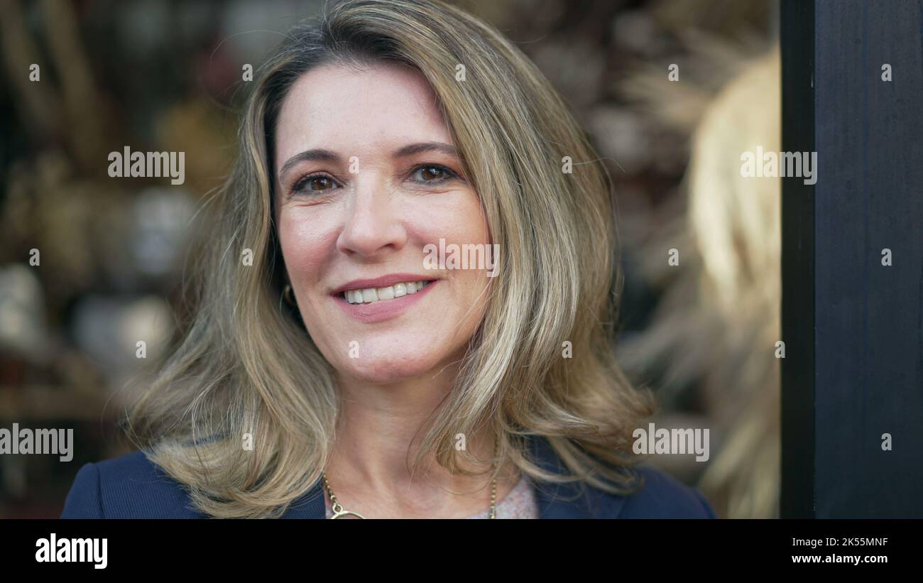 Portrait of a middle age female entrepreneur standing in front of small ...
