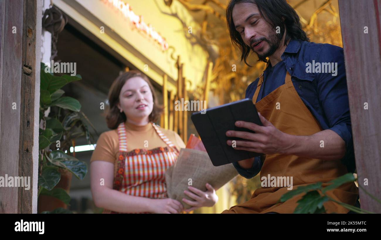 Two young entrepreneur of flower shop. Man calling female work ...