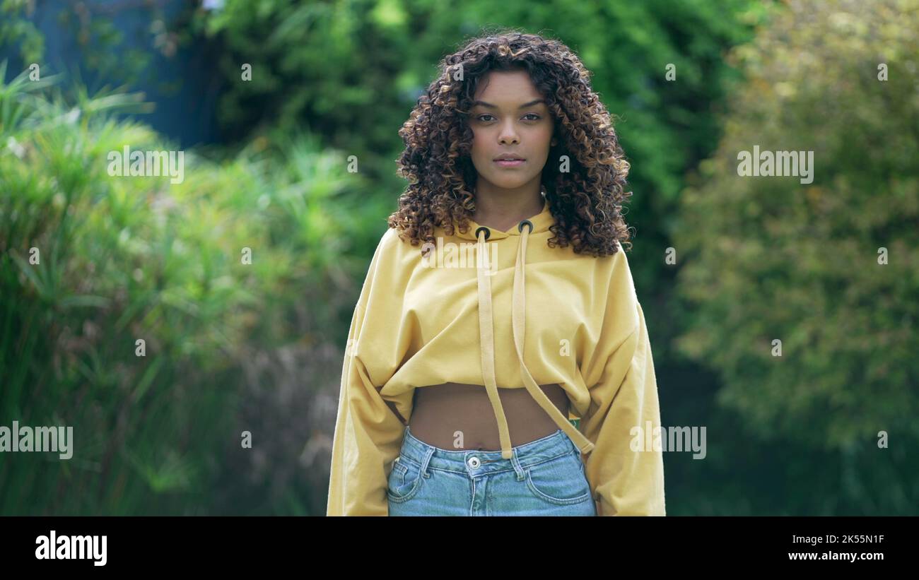 A young black hispanic latina 20s girl standing outdoors looking at ...