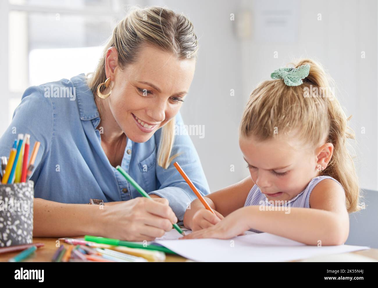A happy mother, girl child drawing on paper and coloring together with ...