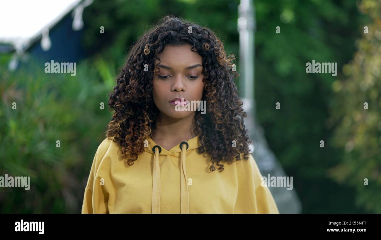 One pensive black young woman standing outdoors in contemplation. A ...