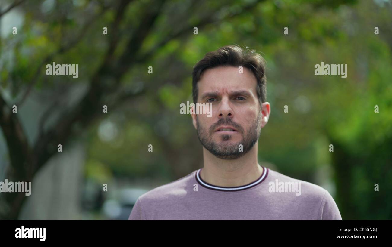 Pensive young man walking outdoors in street. Thoughtful contemplative male person in 30s walks ...