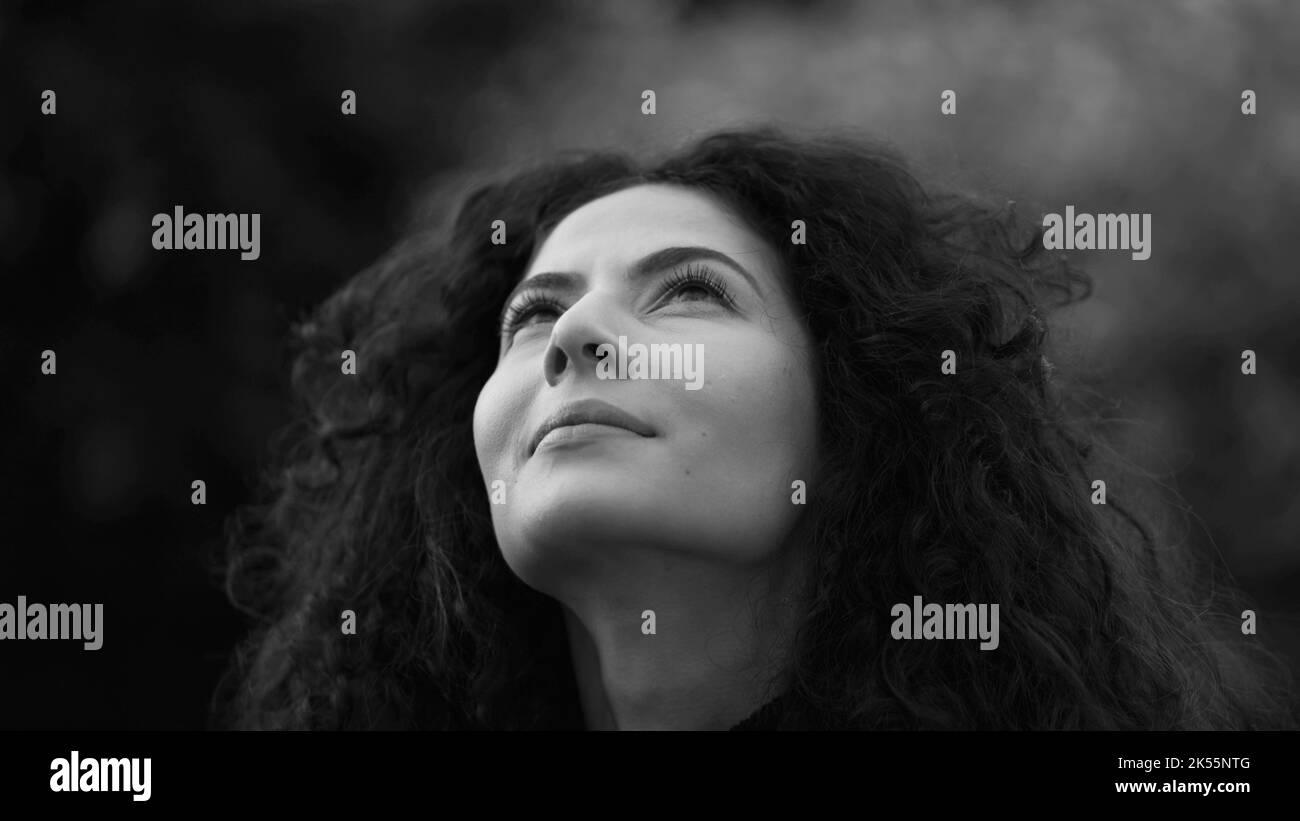Woman standing outdoors in contemplation in monochromatic. Black and ...