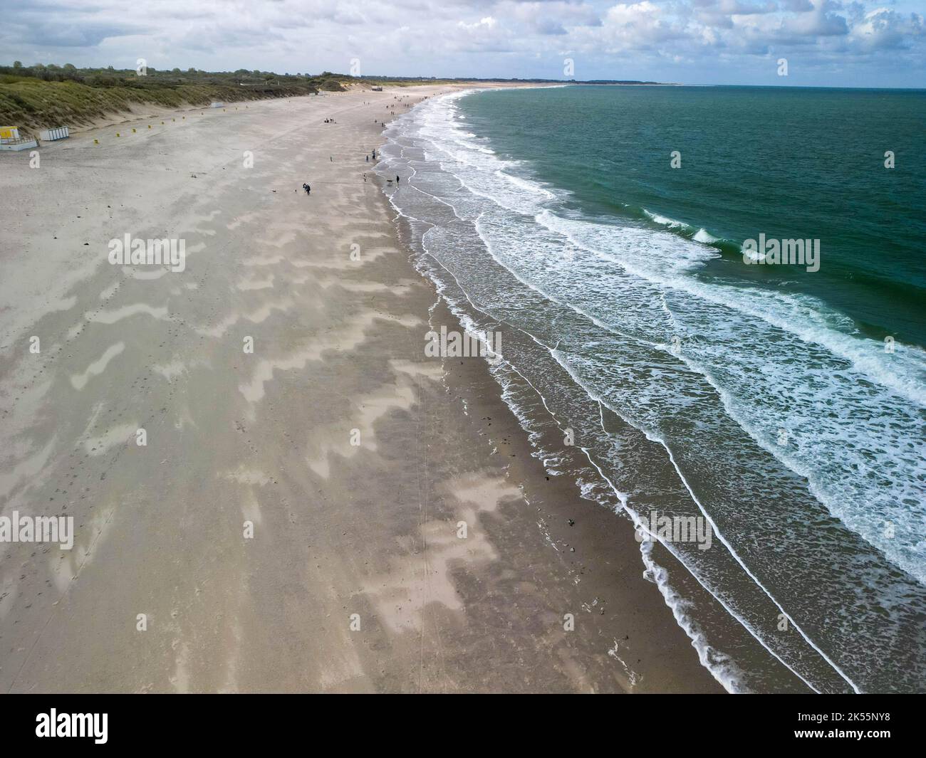 An aerial shot of the ocean waves moving toward the crowded coast in ...