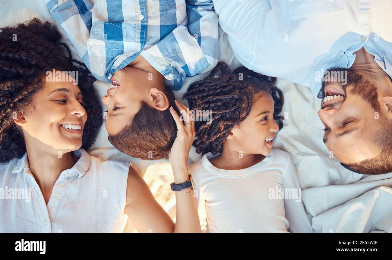 Love, relax and happy family in bed, laughing, bonding and resting in their bedroom together ...