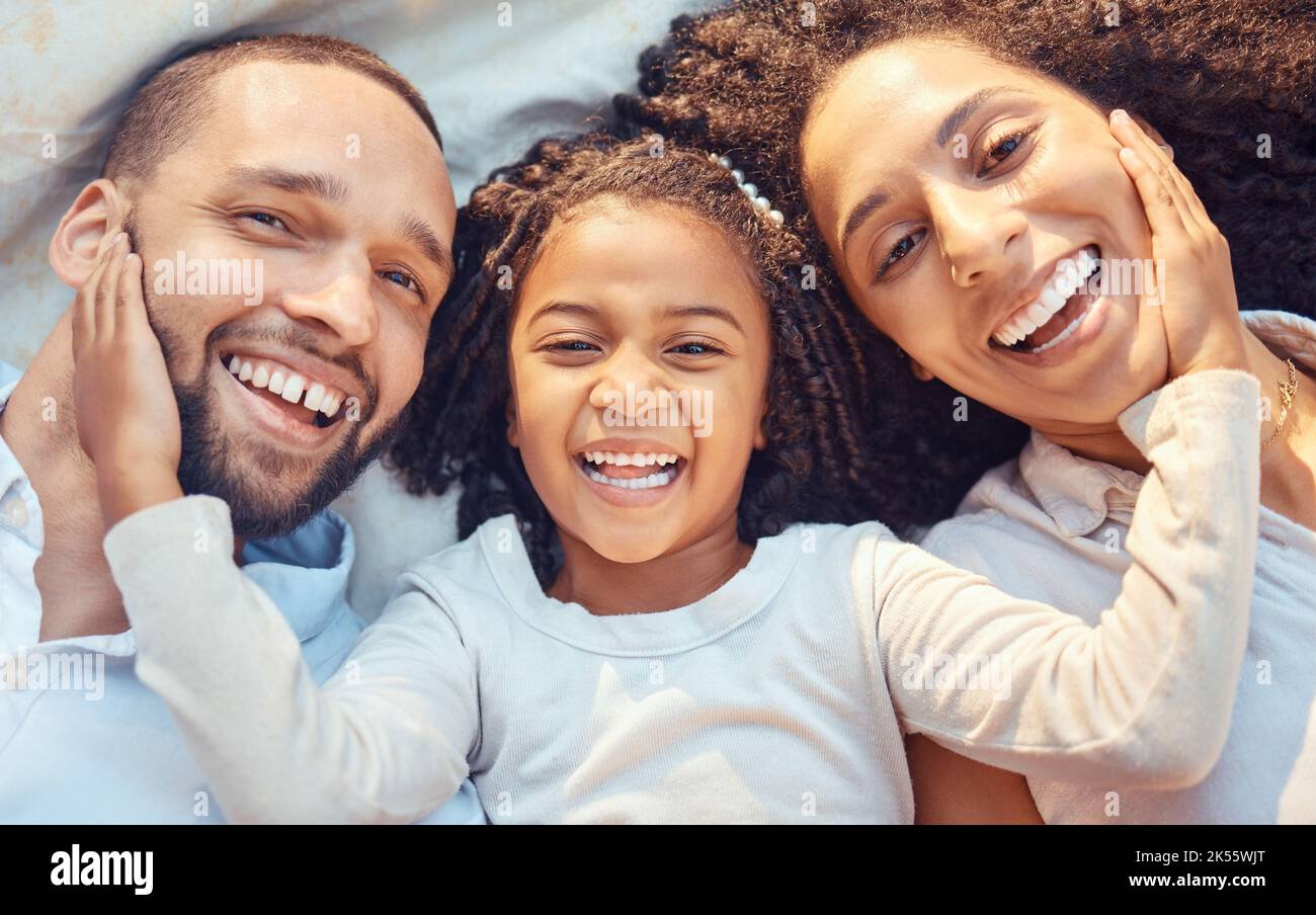 Family, girl and above smile in portrait on bed for happy closeup together to relax together ...