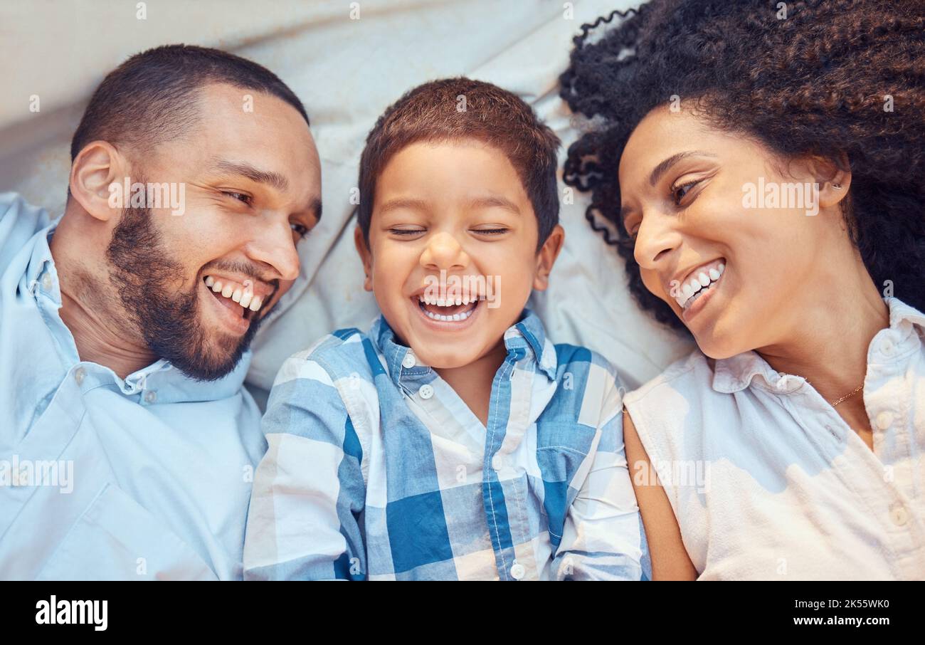 Parents, child and smile in bed for happy closeup together to relax ...