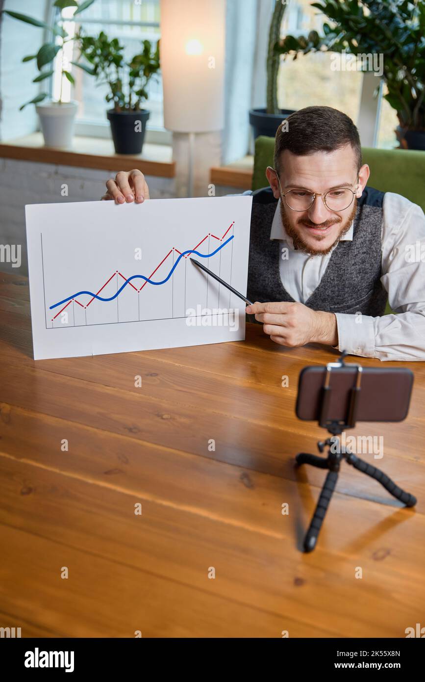Close up male hands with pen pointing on business chart and mobile ...