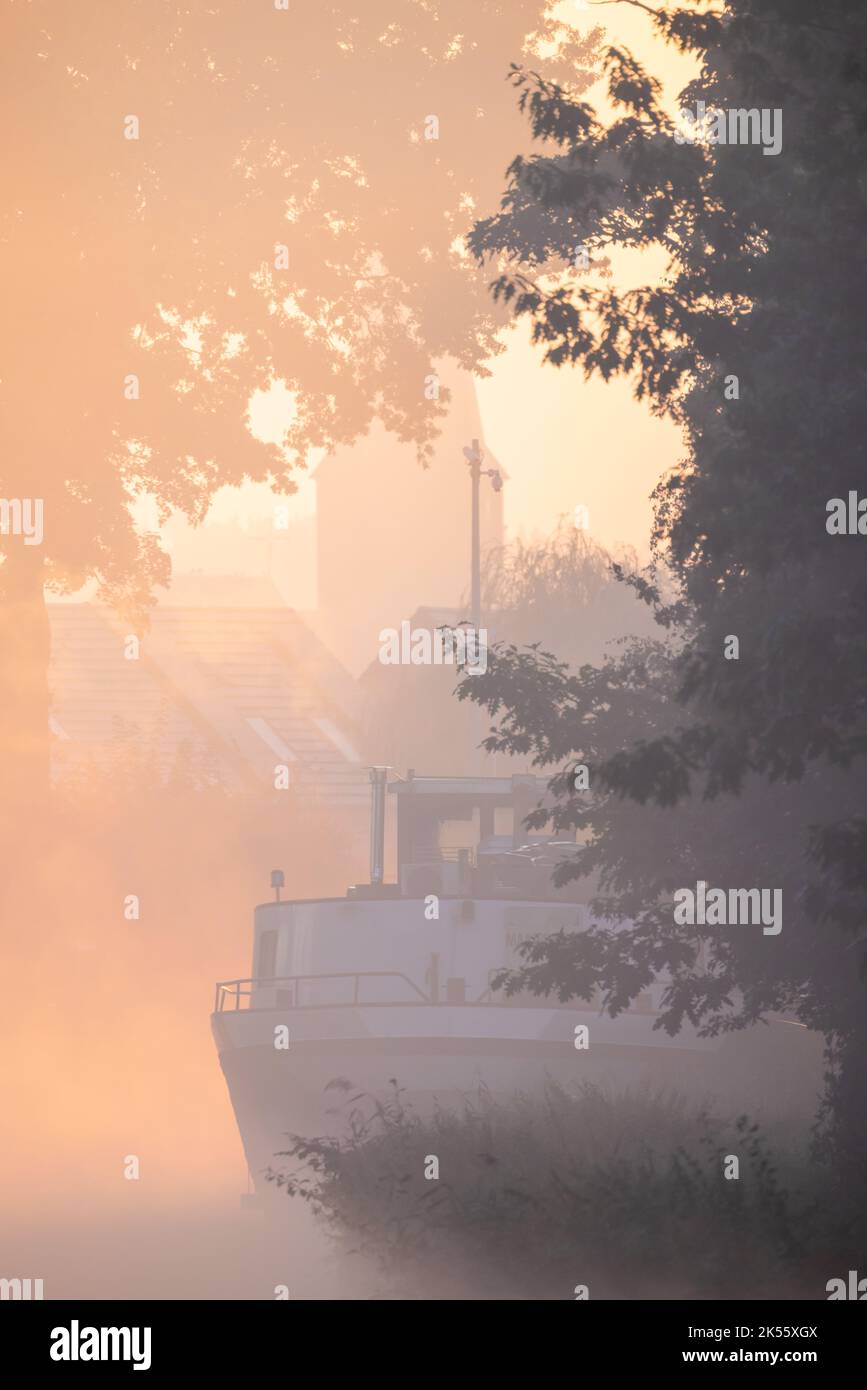 Silhouette of a cargo boat in the fiery red fog on a misty Morning on ...