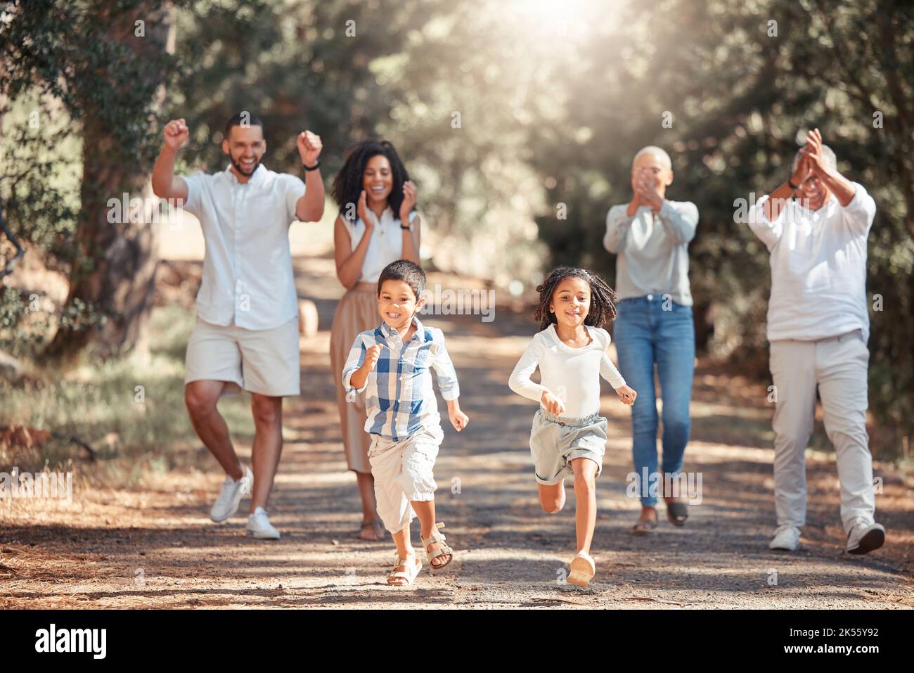 Nature, running and happy family cheering on children in a park having ...