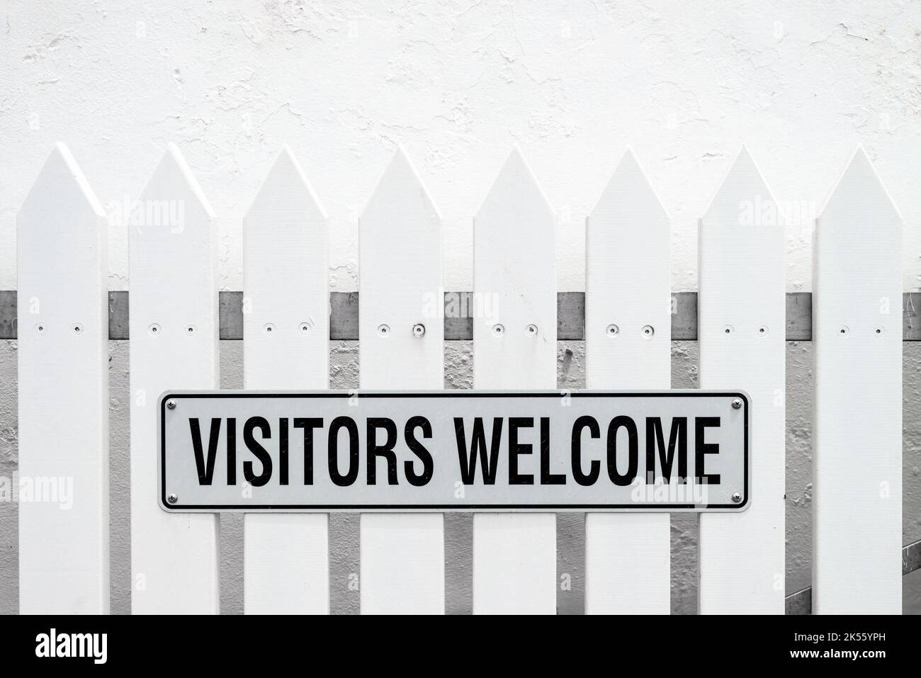 Visitors Welcome sign on the fence against white wall Stock Photo - Alamy