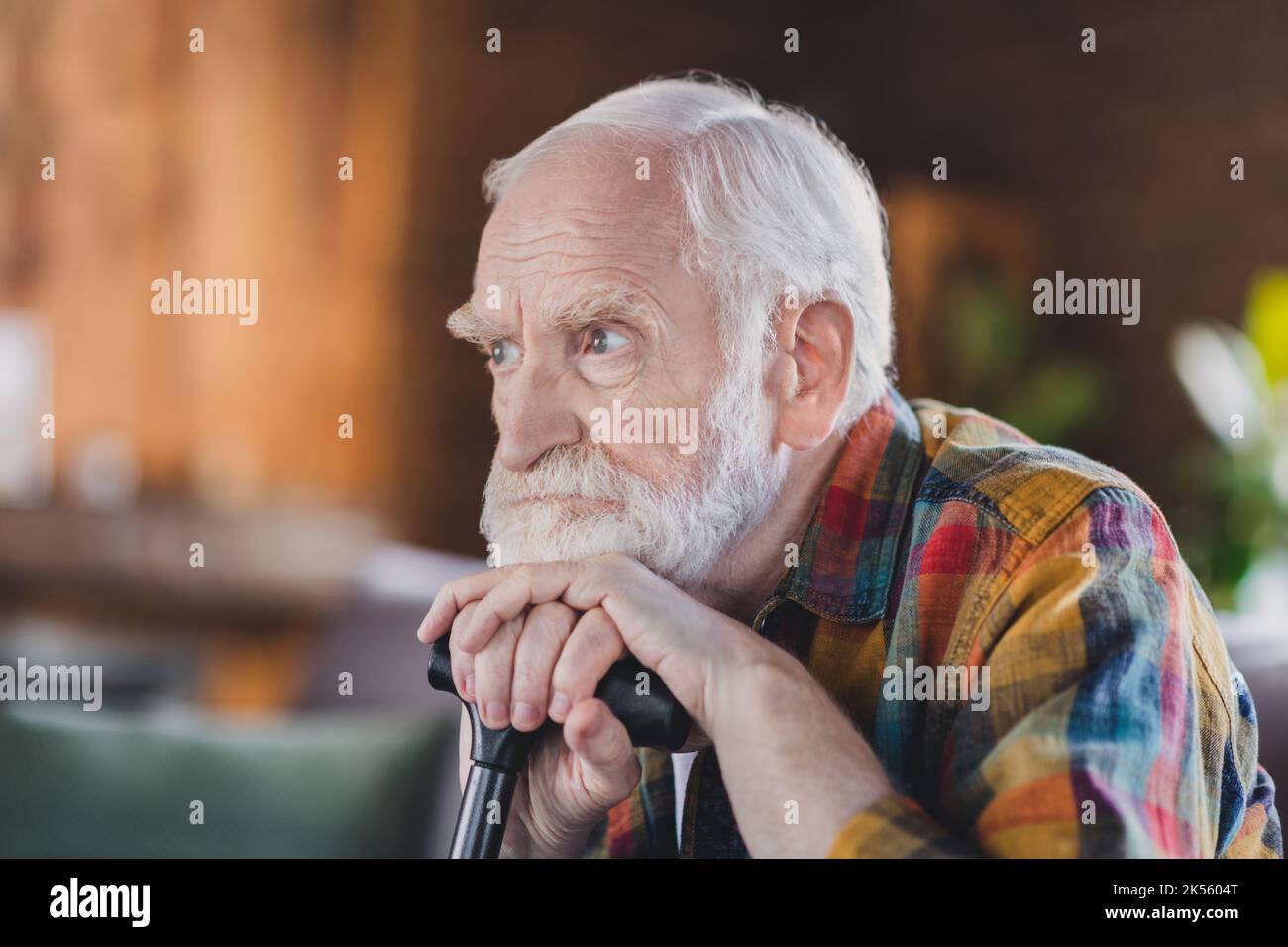 Photo of angry moody man pensioner wear sitting sofa chin arms walking ...