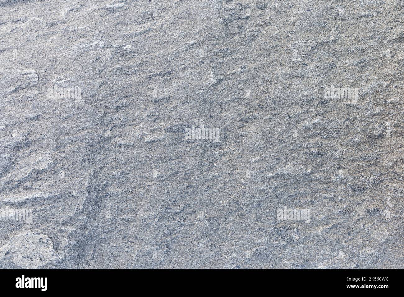 Close-up of a rough light gray granite rock surface texture, front view ...