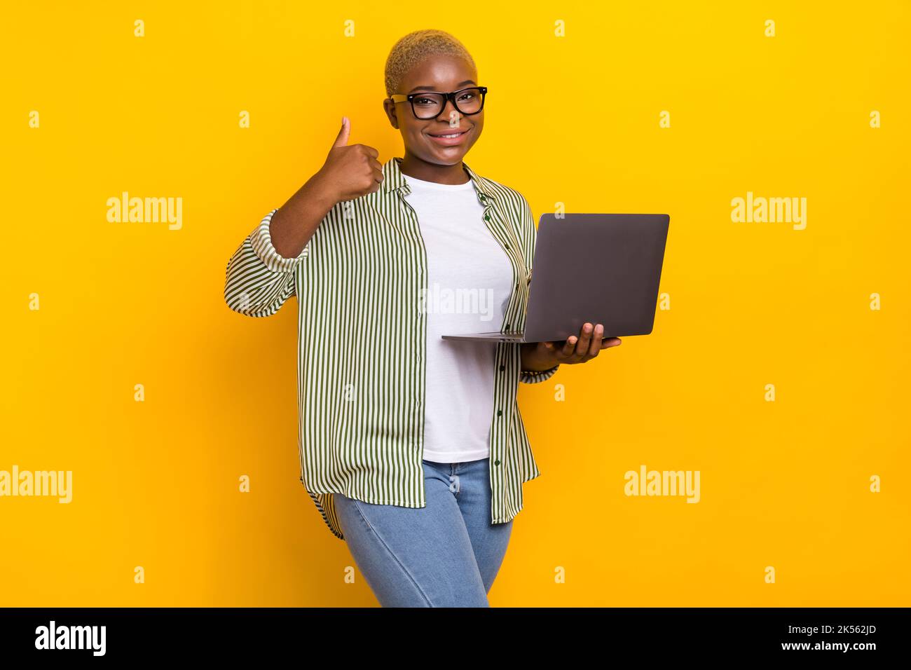 Photo of attractive cheerful girl demonstrate thumb up feedback hold ...