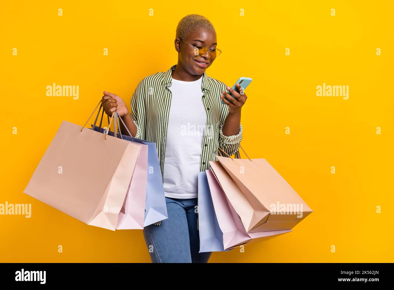 Photo of attractive cheerful girl hold boutique packages use telephone ...