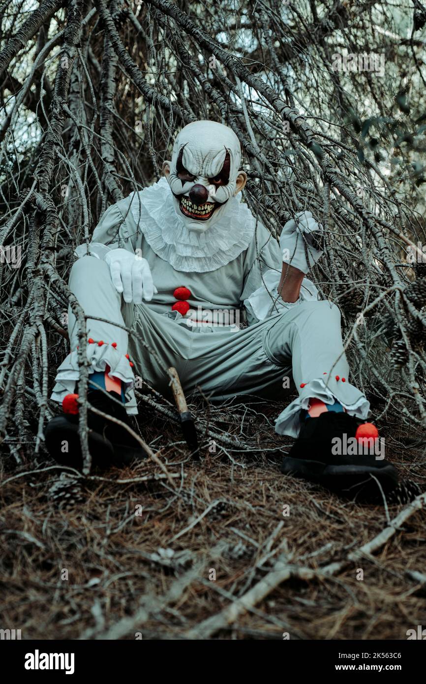 closeup of an evil clown, wearing a gray costume with some ruffles and ...