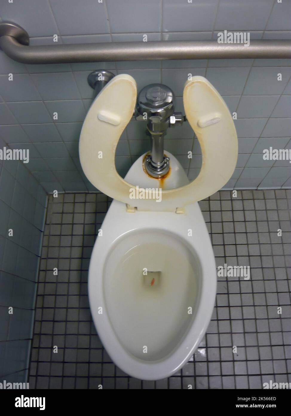 White, but stained, western American style toilet with the toilet seat ...