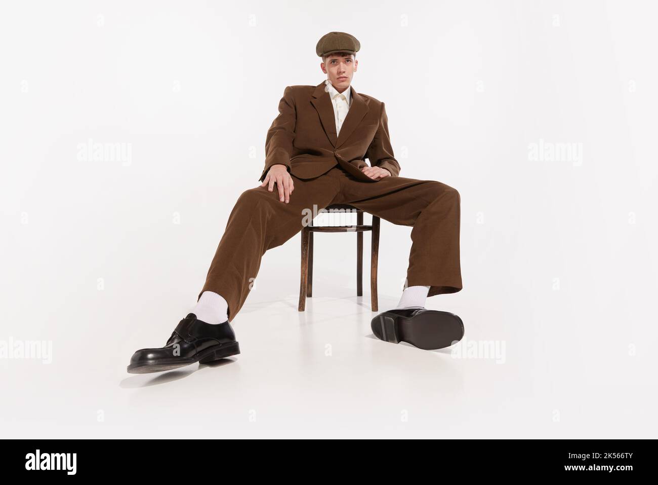 Portrait of young man in vintage, old-fashioned suit sitting on chair ...