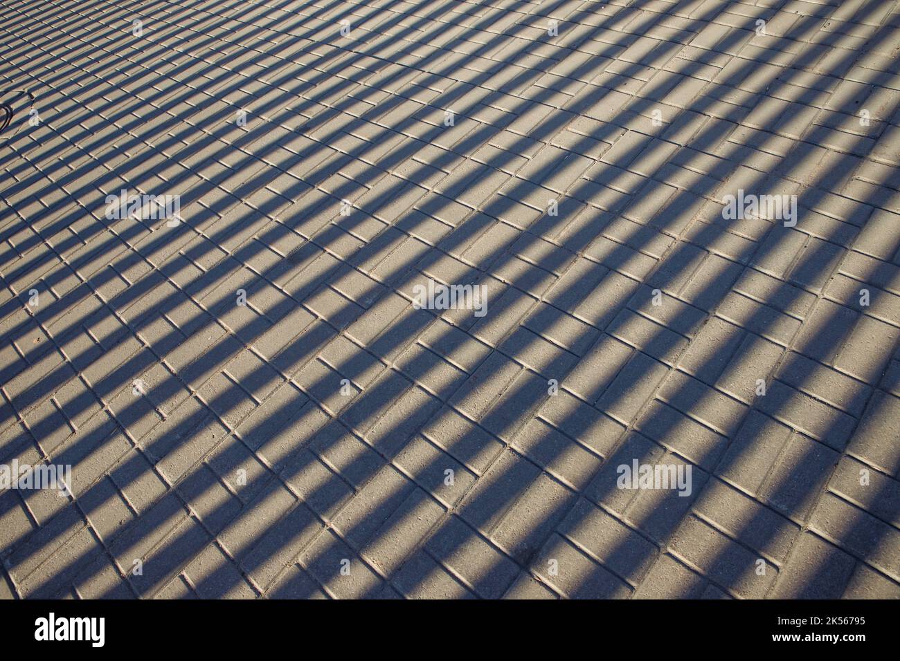 Striped fence shadow on gray street tiles. Footpath, road Stock Photo ...